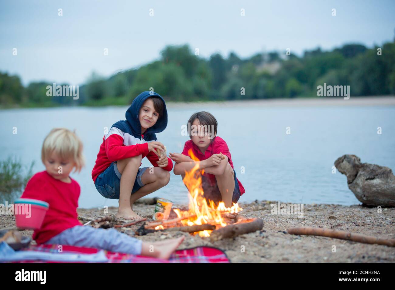 Family having picnic and campfire in the evening near river summertime ...
