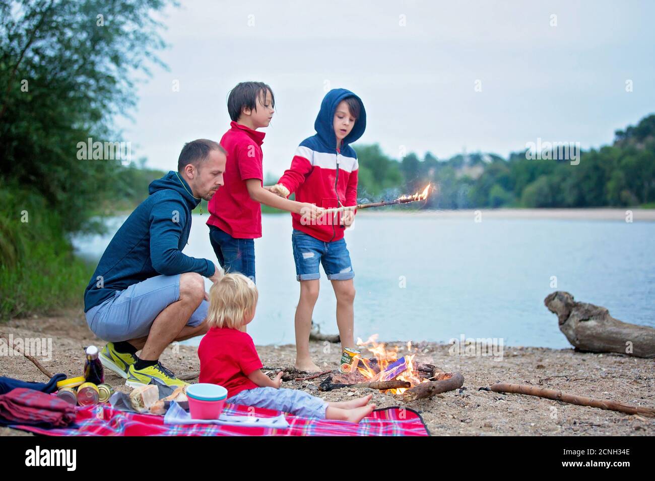 Family having picnic and campfire in the evening near river summertime ...