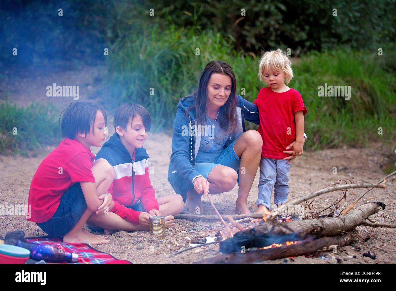 Family having picnic and campfire in the evening near river summertime ...