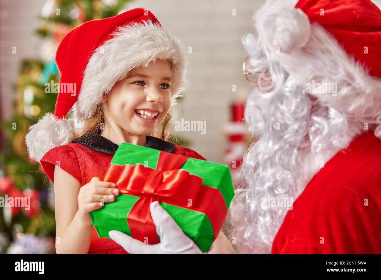 Santa Claus giving a present to a little cute girl Stock Photo - Alamy