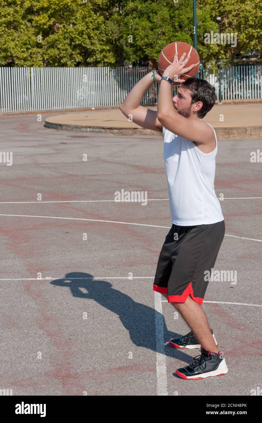 Vertical shot of a young male playing basketball in a sports ground ...