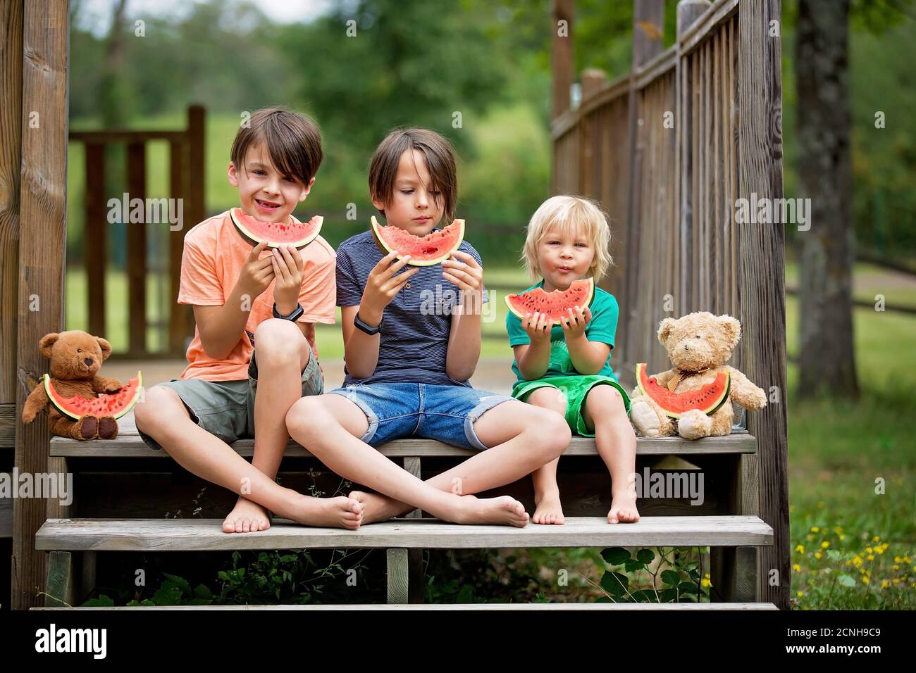 Three children, boy brothers, eating watermelon, sitting on stairs ...