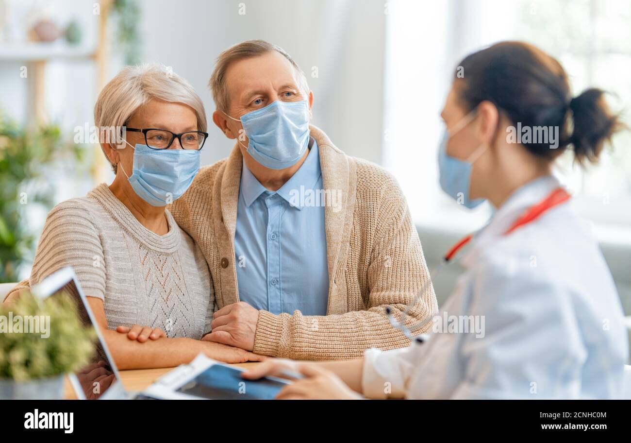Doctor and senior couple wearing facemasks during coronavirus and flu ...