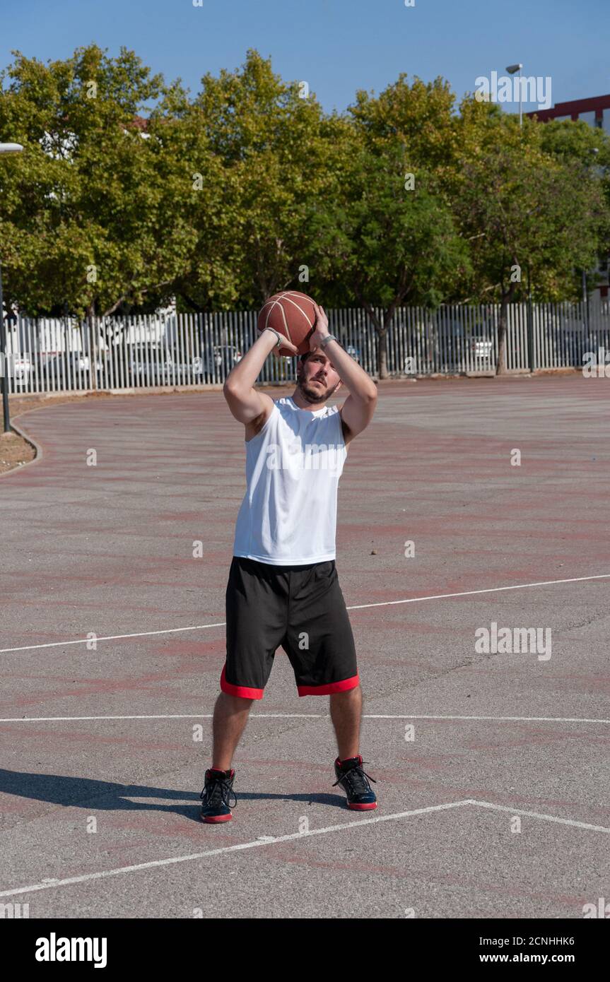 Vertical shot of a young male playing basketball in a sports ground ...