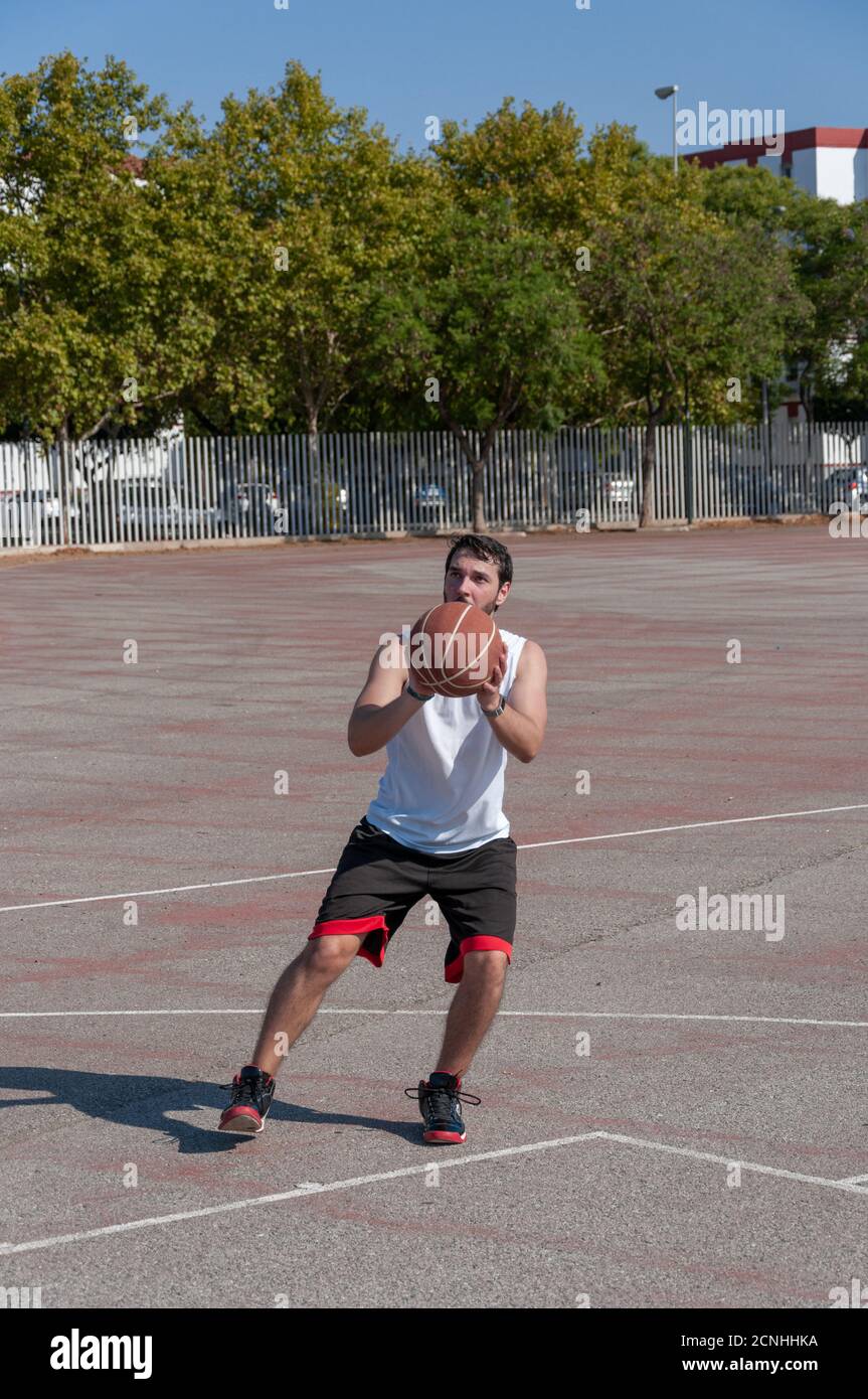 Vertical shot of a young male playing basketball in a sports ground ...