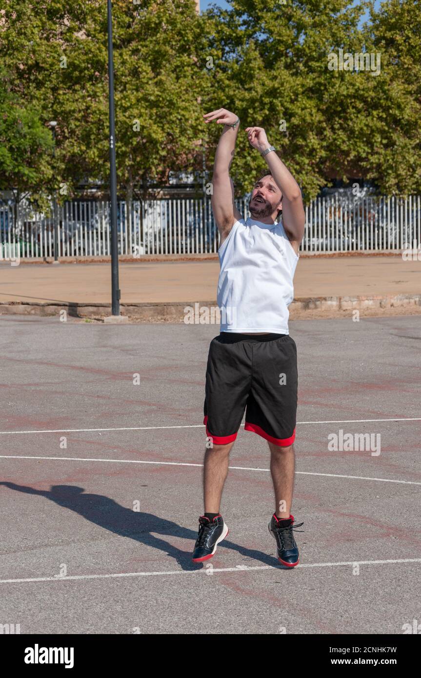 Vertical shot of a young male playing basketball in the sports ground ...
