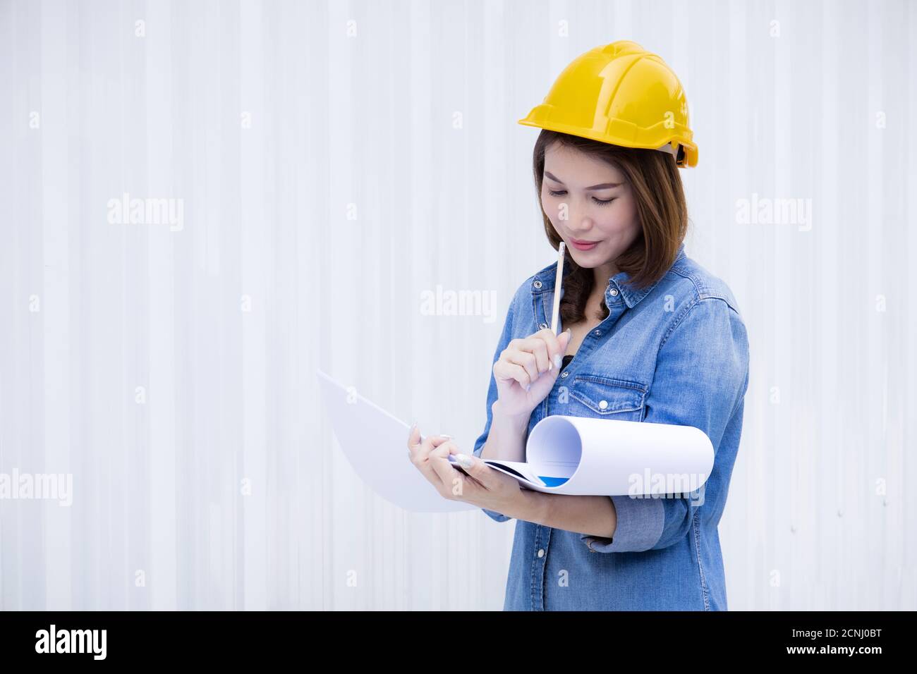 Beautiful Asian female engineer in jeans dress wearing yellow safety ...
