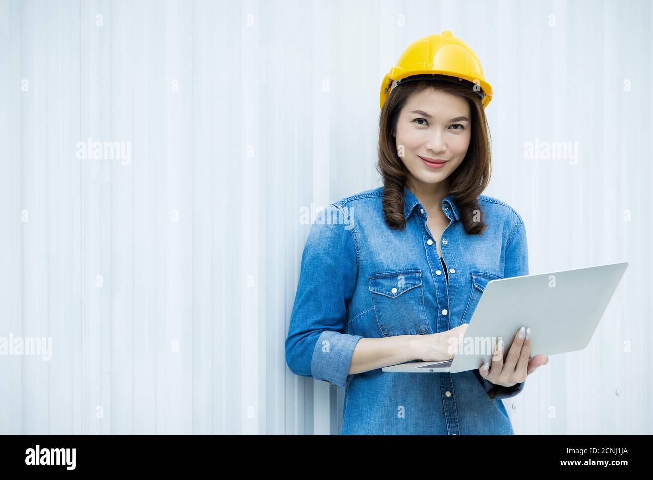 Beautiful Asian female engineer in jeans dress wearing yellow safety ...