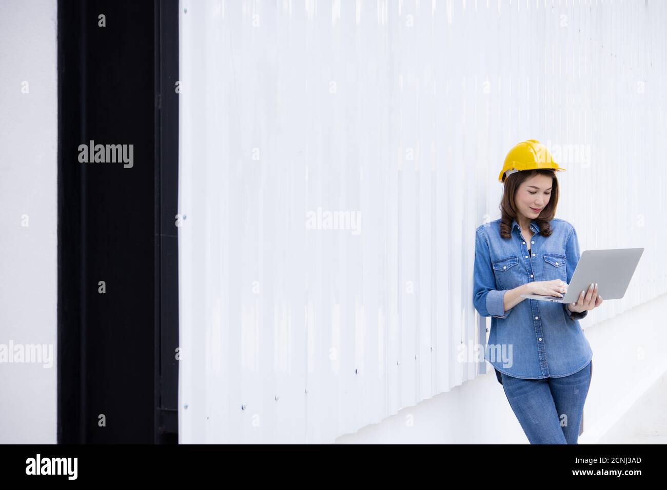 Beautiful Asian female engineer in jeans dress wearing yellow safety ...