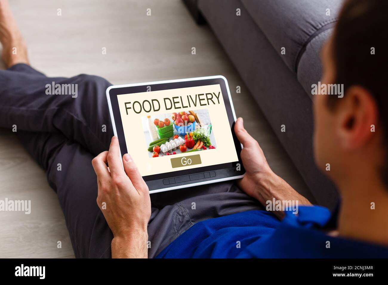 Man ordering take away food by internet with the tablet while lying at ...