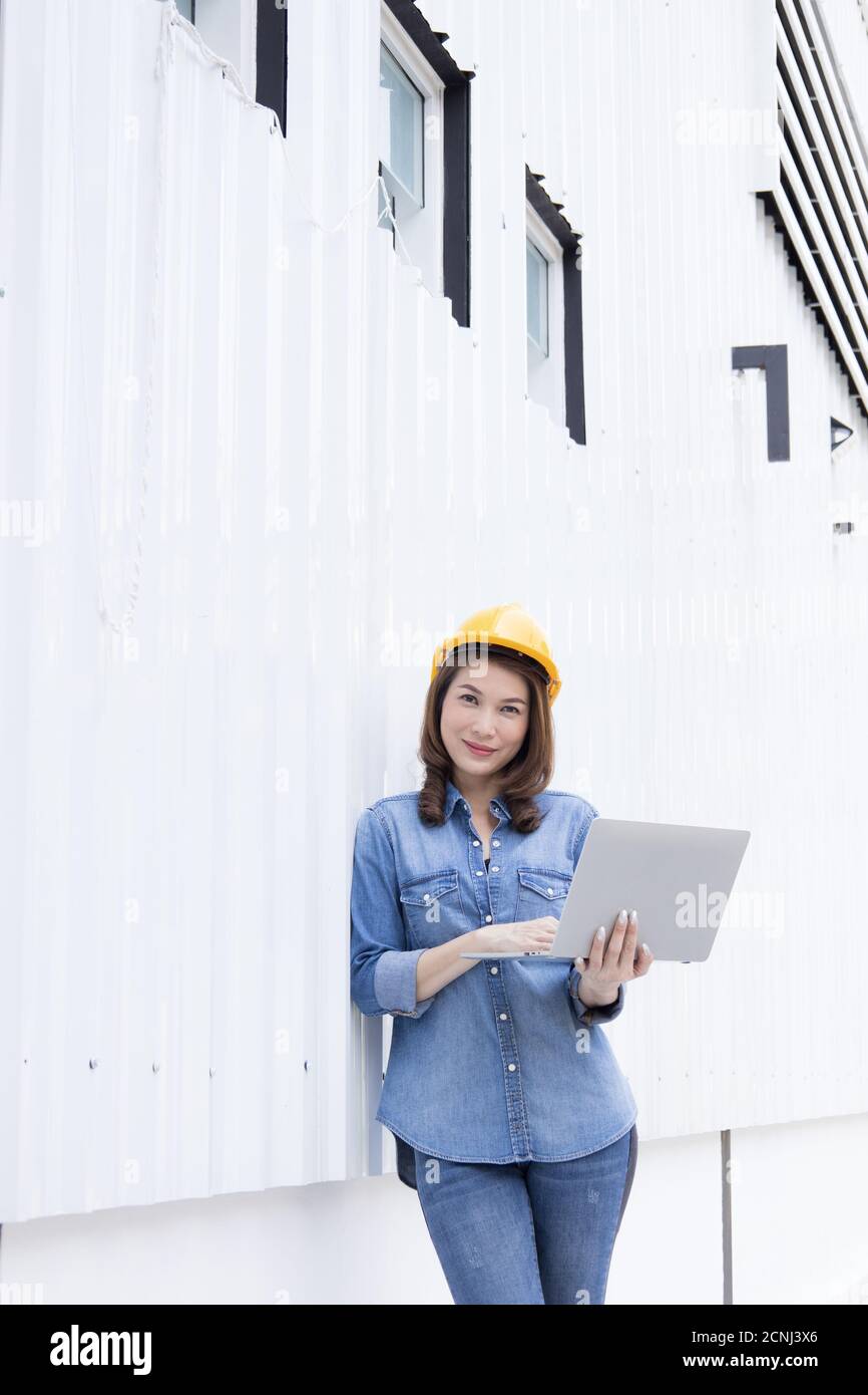Beautiful Asian female engineer in jeans dress wearing yellow safety ...