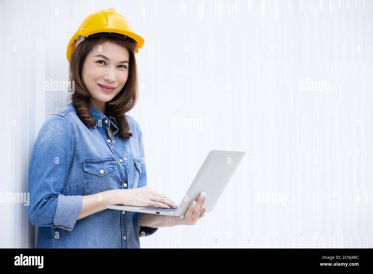 Beautiful Asian female engineer in jeans dress wearing yellow safety ...