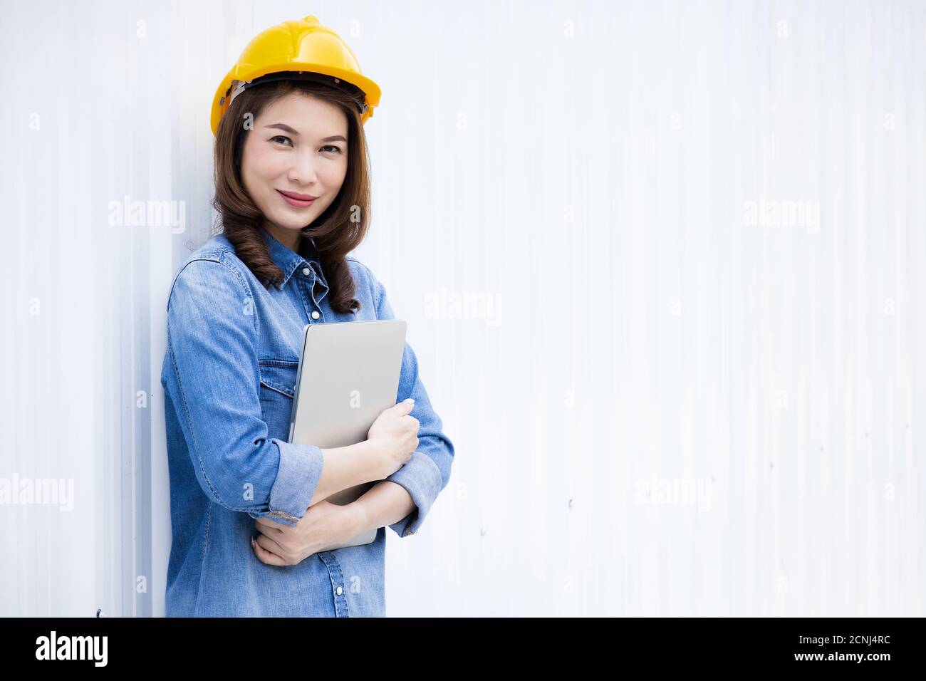Beautiful Asian female engineer in jeans dress wearing yellow safety ...
