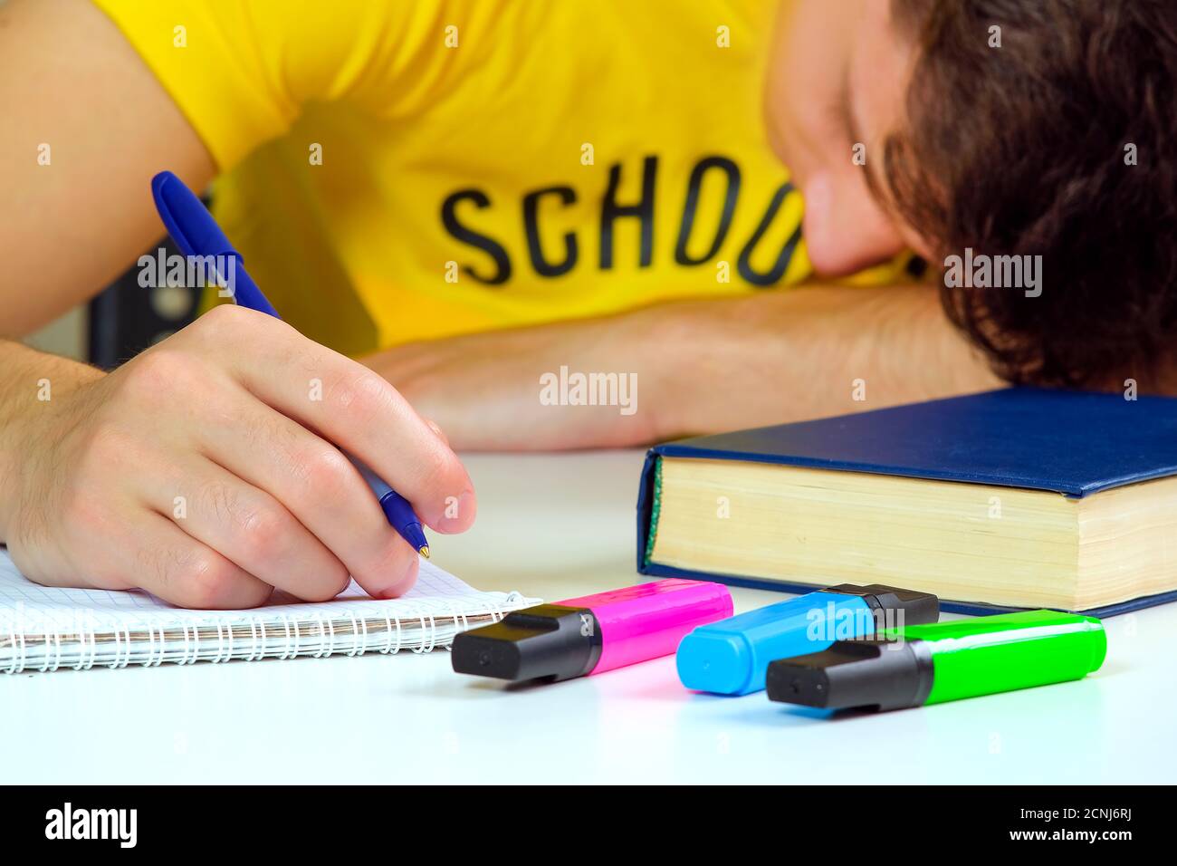 The student is sitting at a table with a textbook and a notebook ...