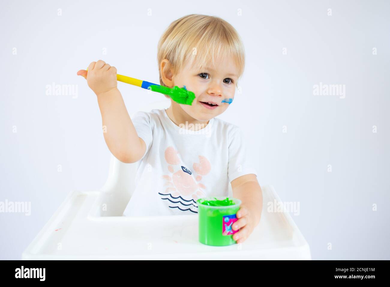 Amazed toddler boy with colorful paints on face isolated on white ...