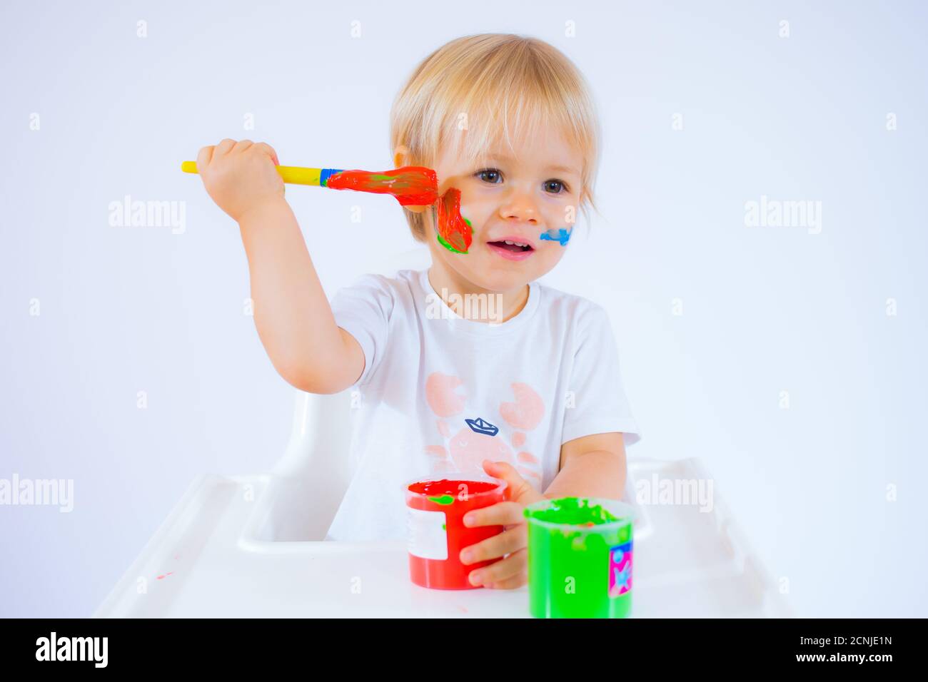 Amazed toddler boy with colorful paints on face isolated on white ...
