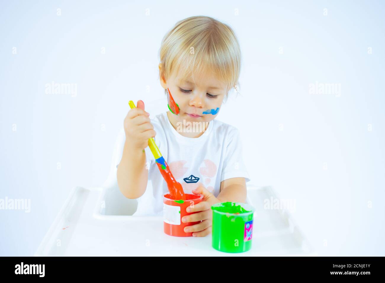 Amazed toddler boy with colorful paints on face isolated on white ...