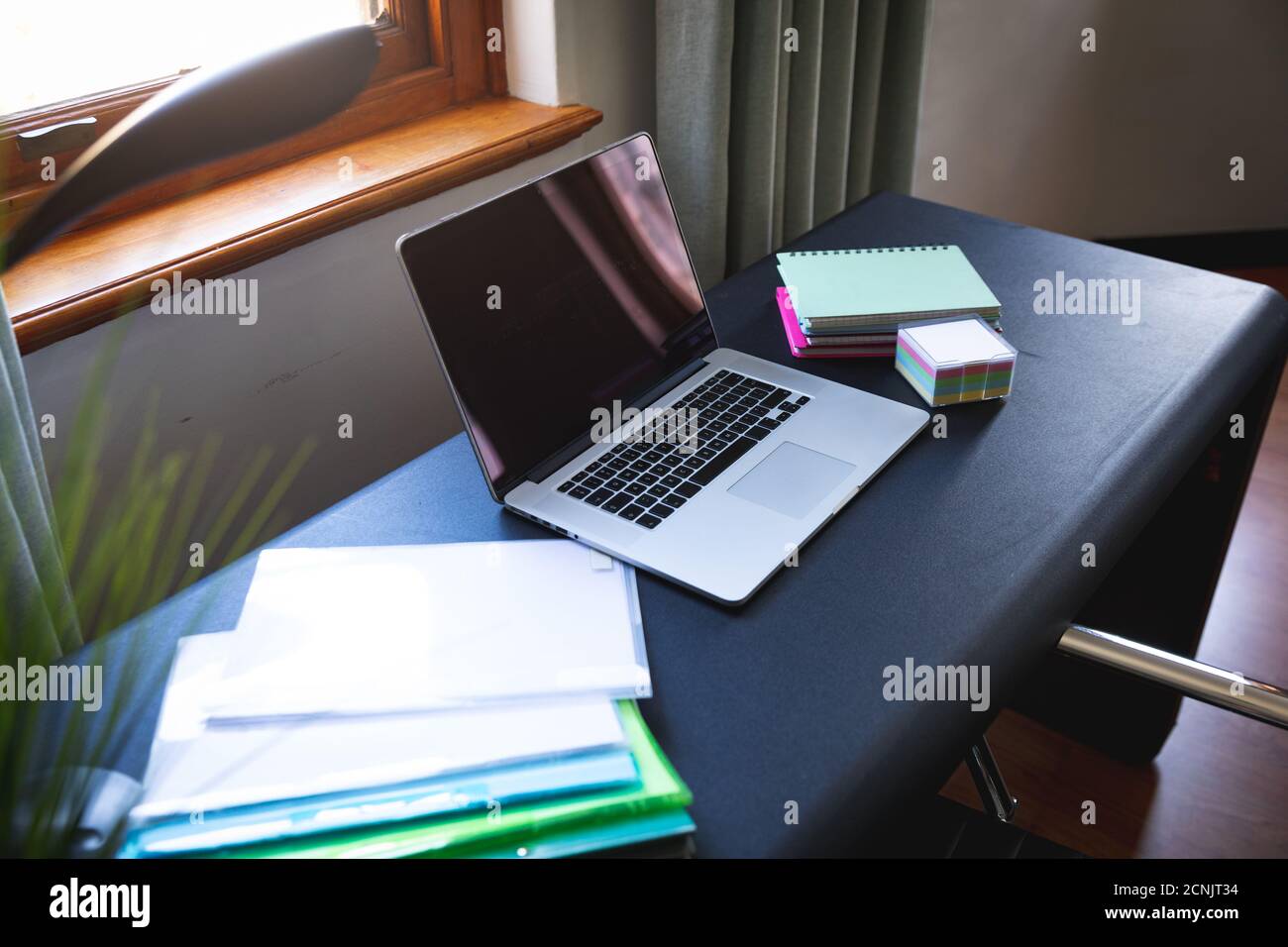 General view of home office grey desk with laptop computer, documents ...