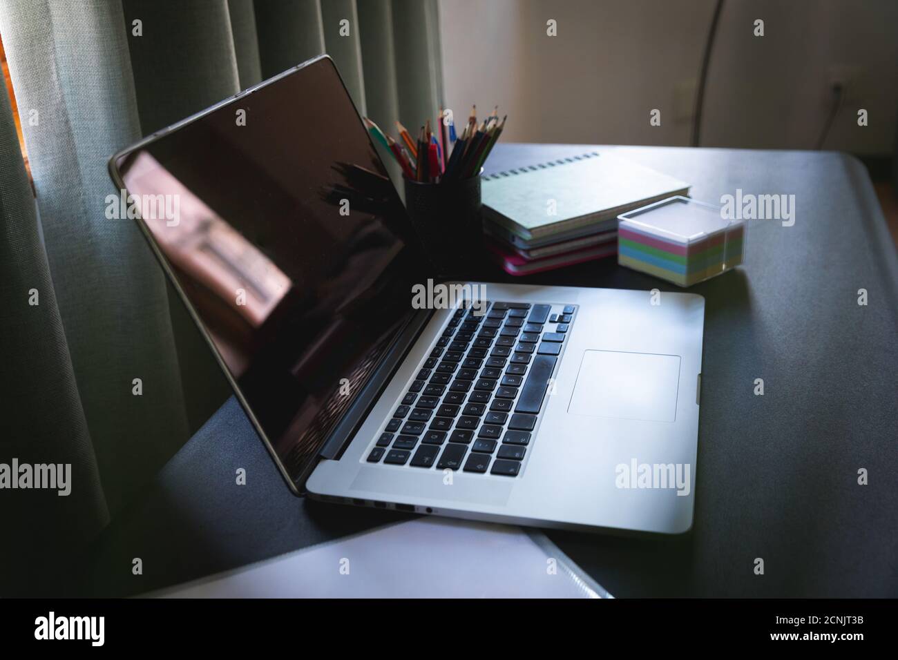 General view of home office grey desk with laptop computer, documents ...