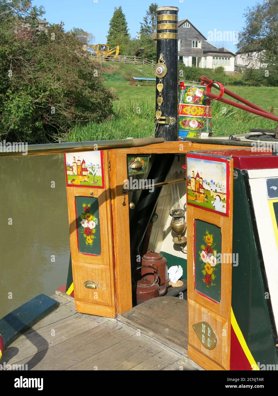 The stern of a traditionally decorated narrowboat with the brightly ...