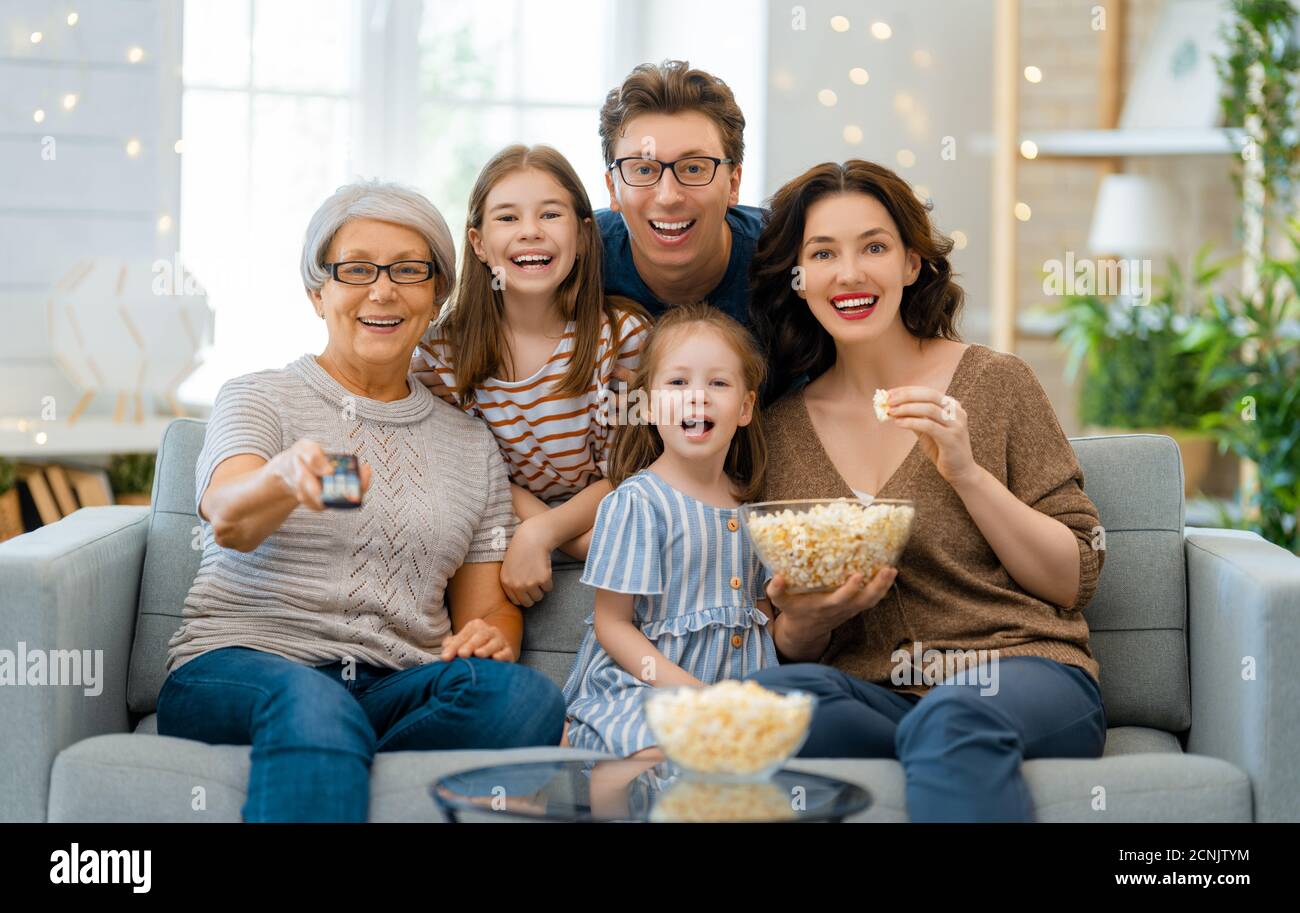 Happy family watching projector, TV, movies with popcorn in the evening ...