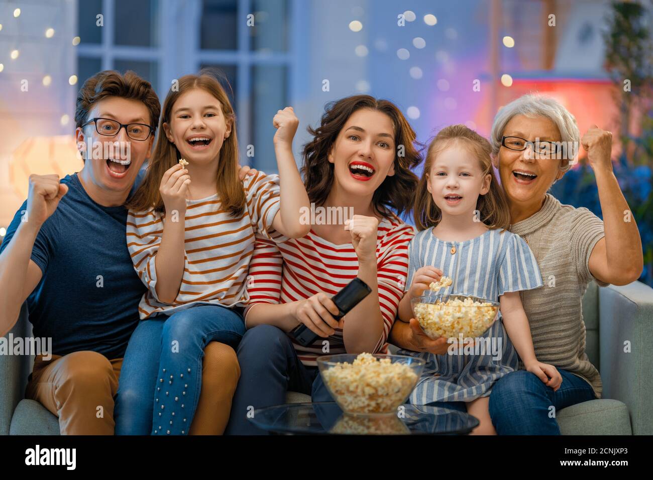 Happy family watching projector, TV, movies with popcorn in the evening ...