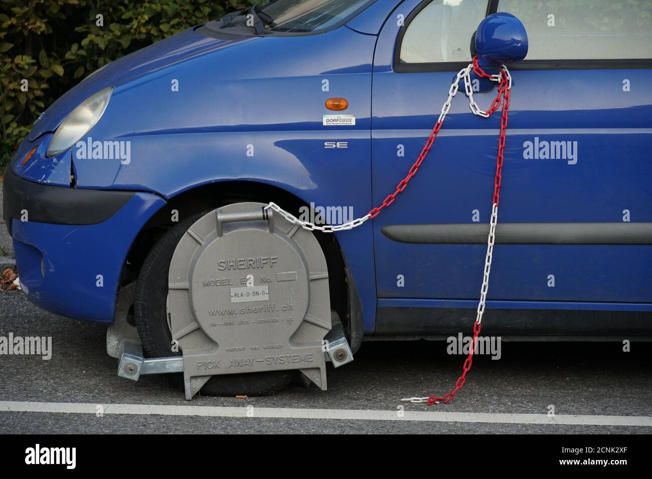 Wheel clamp installed on a wheel of an incorrectly parked car. A chain ...