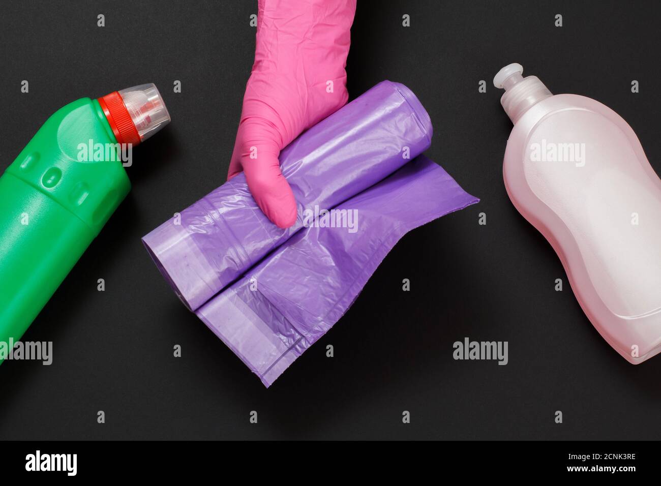 Woman's hand in a protective glove with garbage bags and a washing and ...