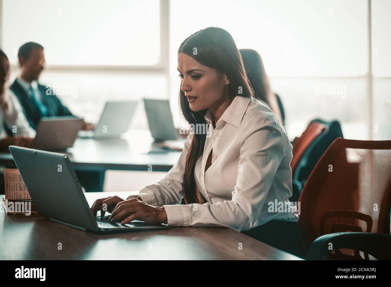 Office woman types text on laptop at workplace. There are other ...