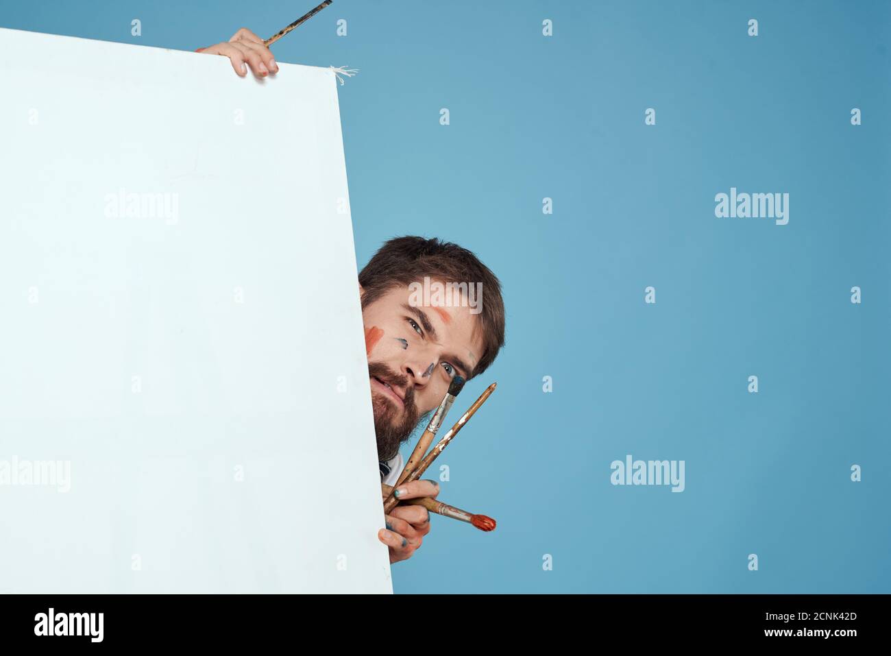 Male artist backs up behind easel brush art creativity blue background ...