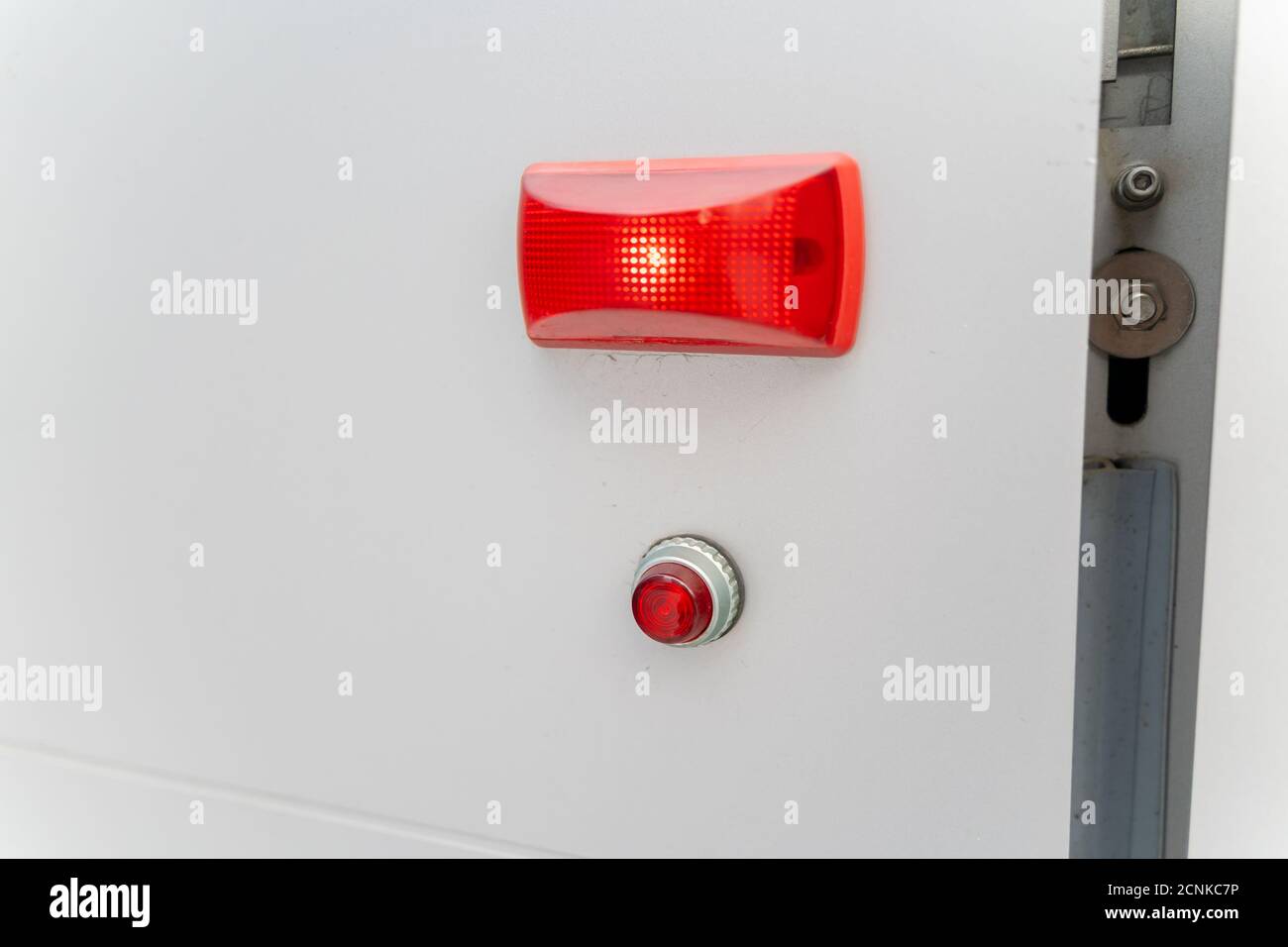 A fire alarm button and a light attached integrally to the gray wall ...