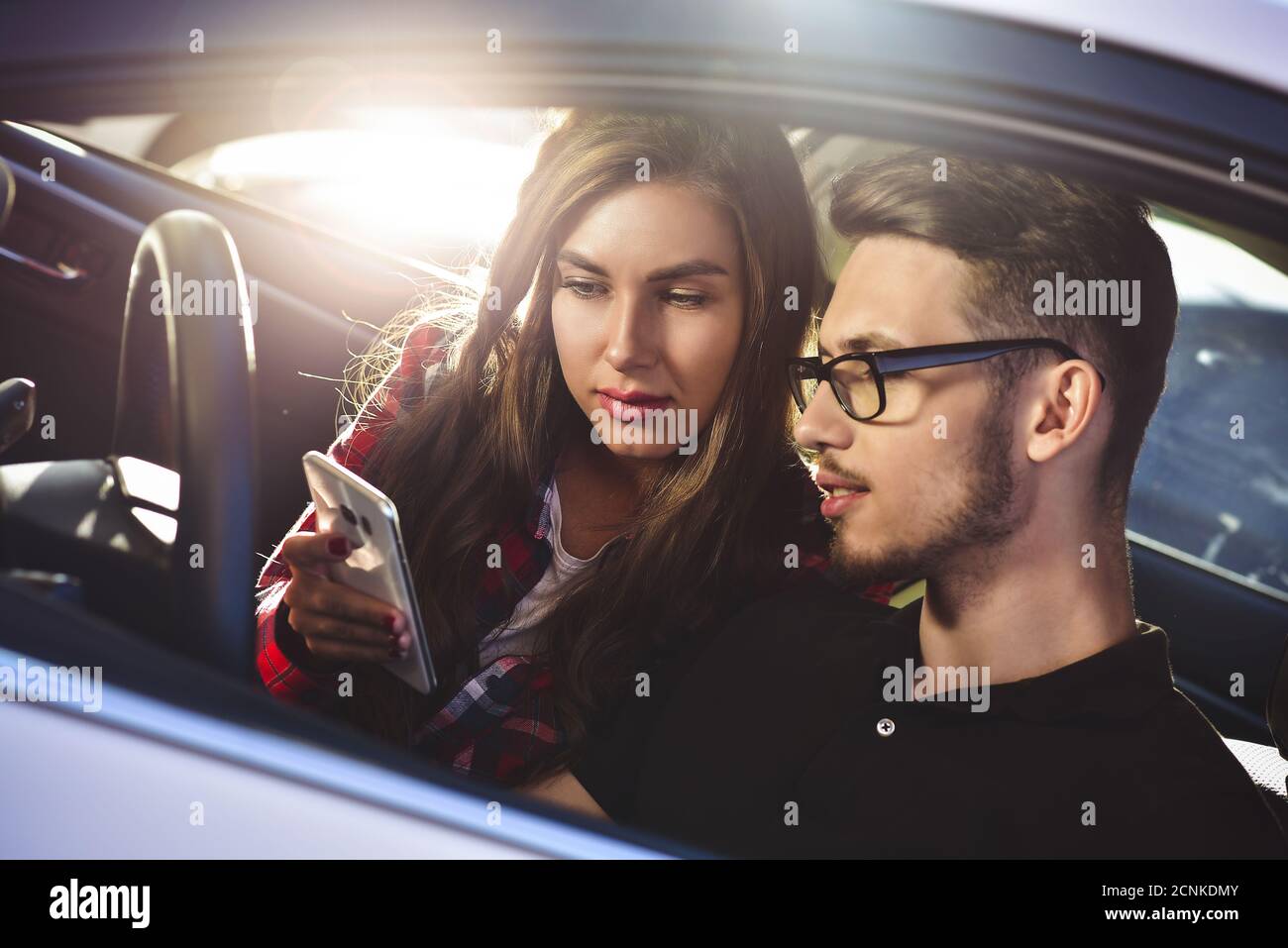 Young caucasian couple in car having fun on road trip and use a ...