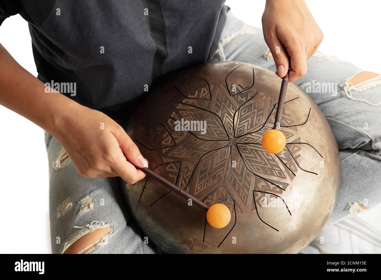 A close up of hands playing the hank drum on white studio background ...
