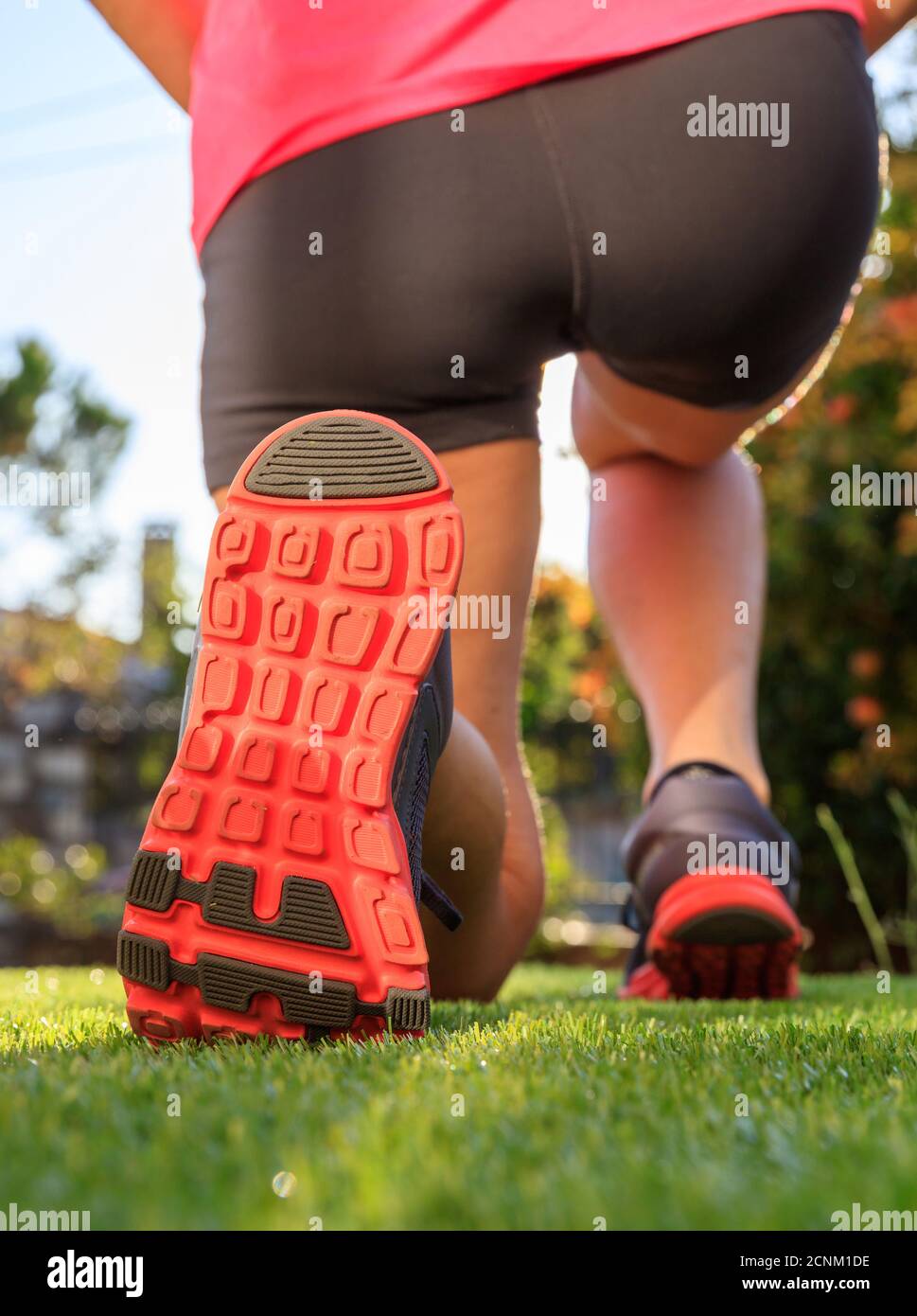 Woman athlete runner feet running on the grass, closeup on shoes ...