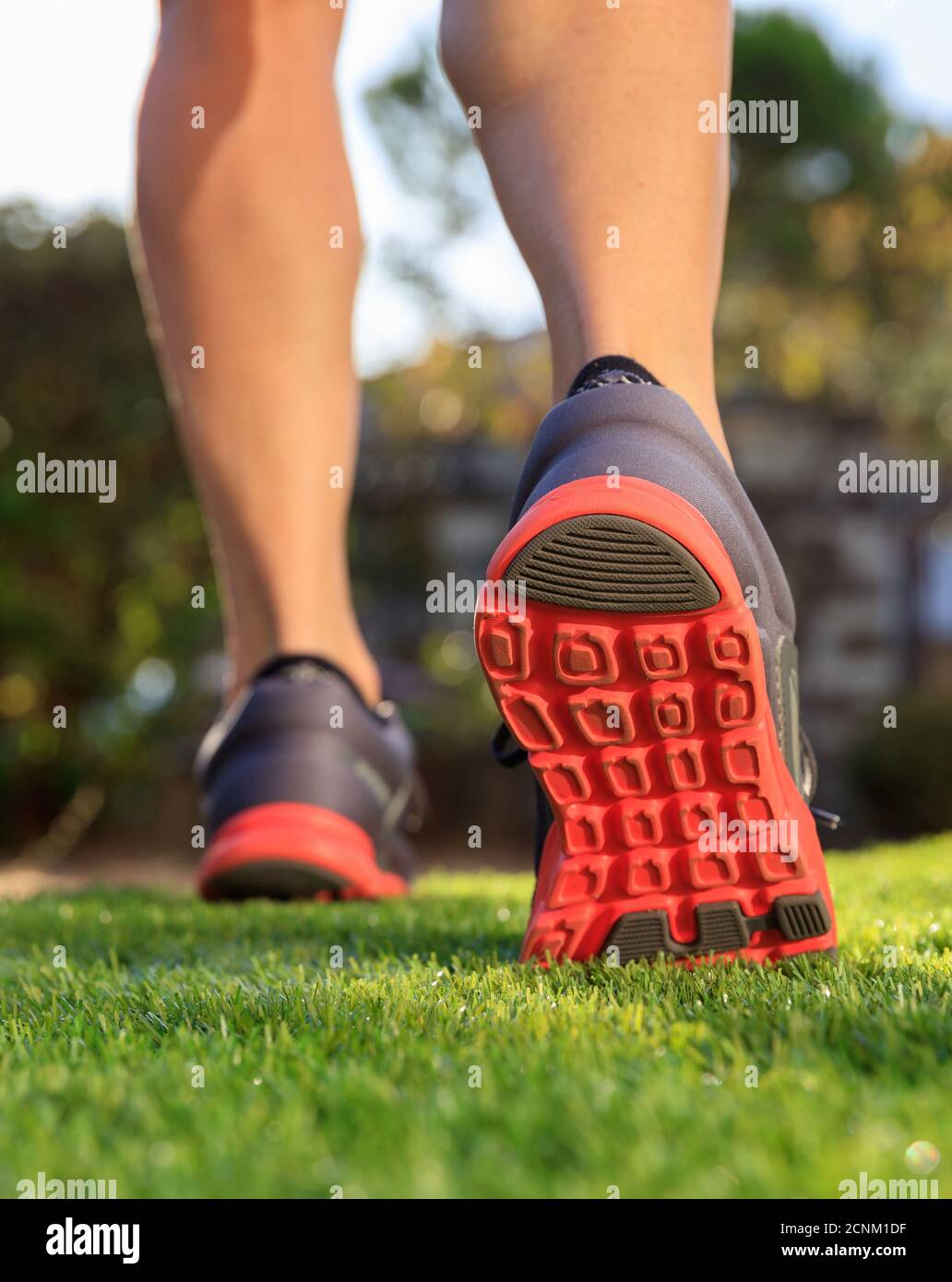 Woman athlete runner feet running on the grass, closeup on shoes ...