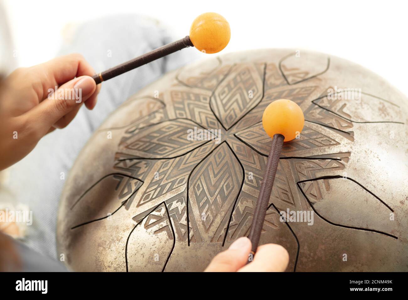 A close up of hands playing the hank drum on white studio background ...