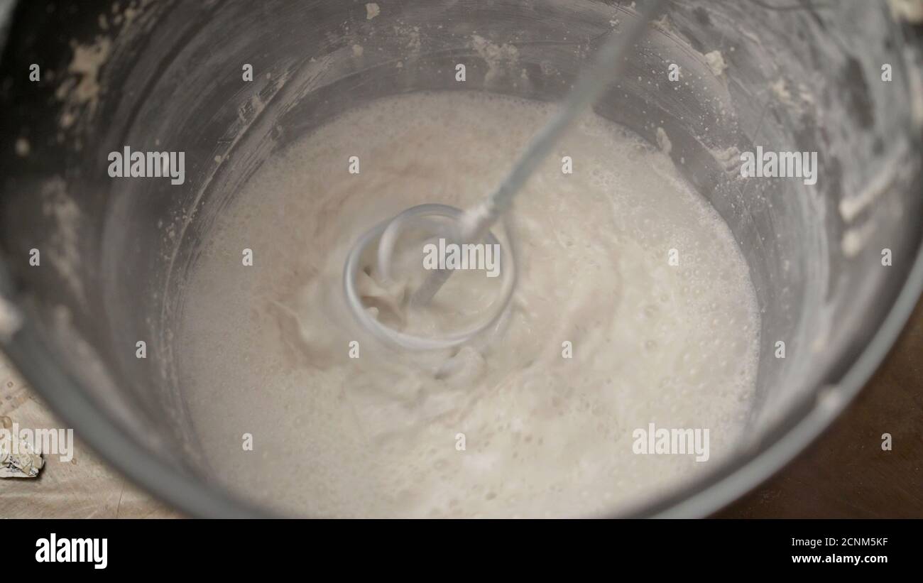 Mixing plaster solution in a bucket, using an electric drill Stock ...