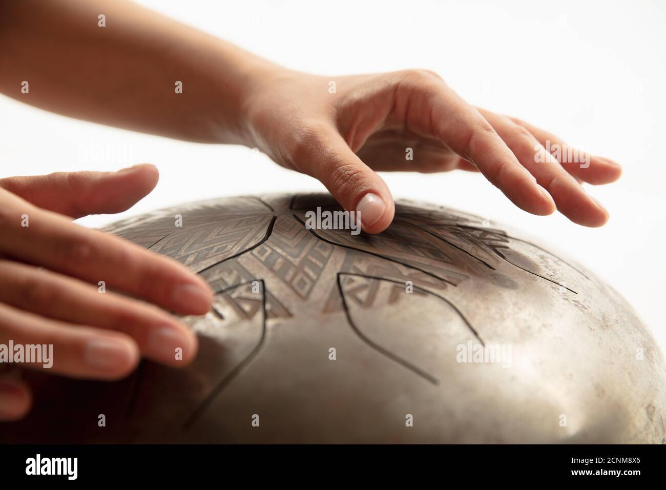 A close up of hands playing the hank drum on white studio background ...