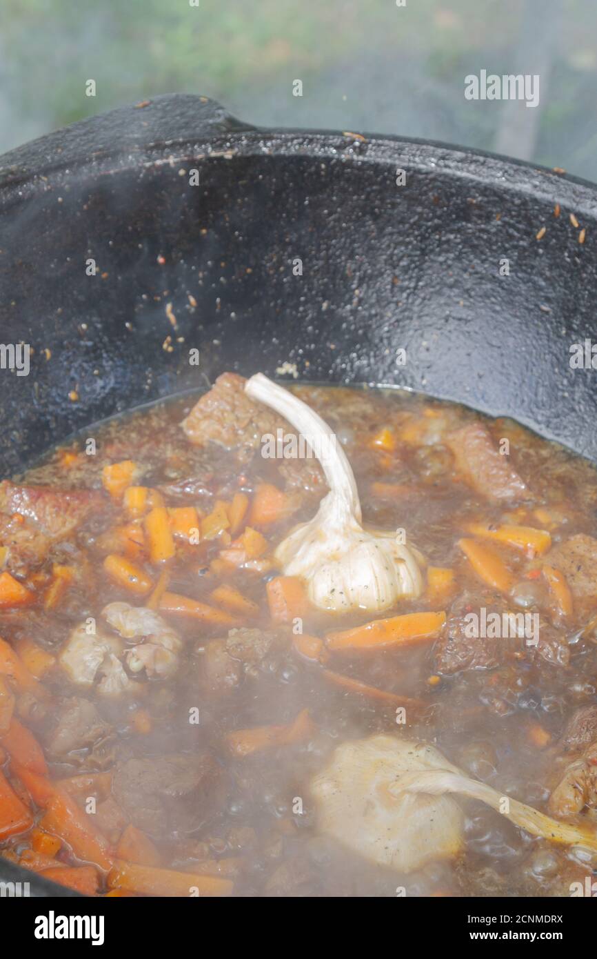 Cooking pilaf in a cauldron on the grill outside in the summer Stock ...
