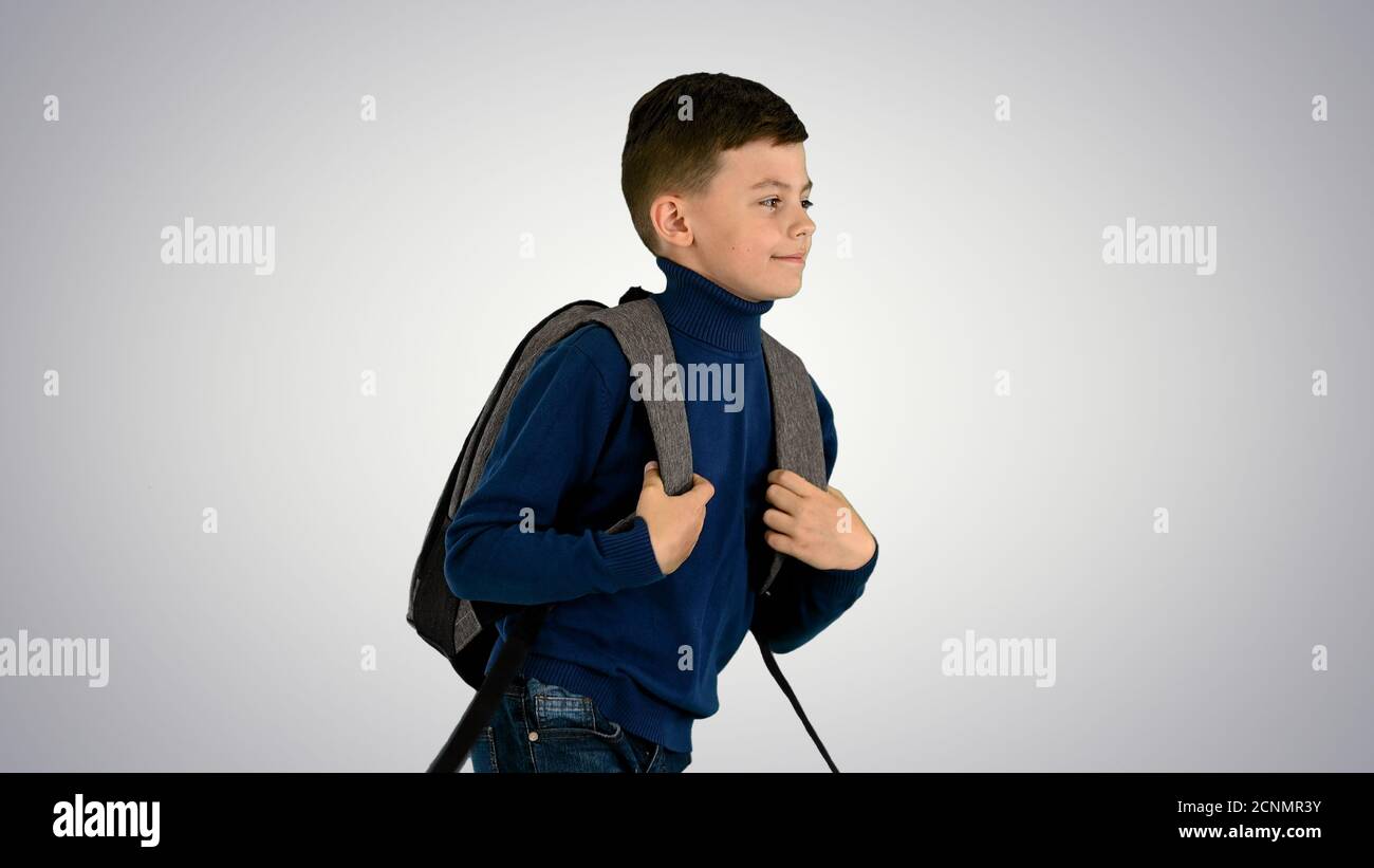 Cheerful boy in polo neck walking with a backpack on gradient ba Stock ...