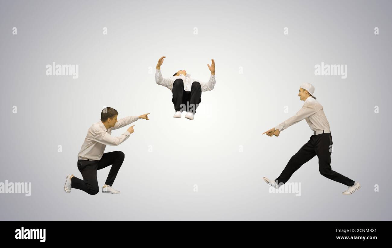Three guys in white shirts dancing in synch looking at camera on ...