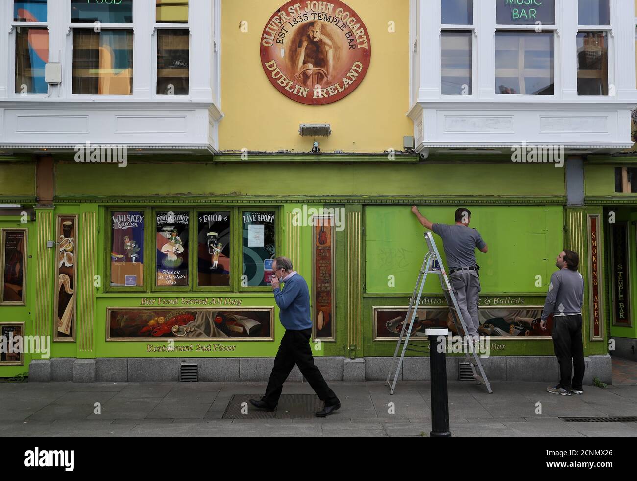 Workers board up the windows of Oliver St. John Gogarty's pub in Dublin ...