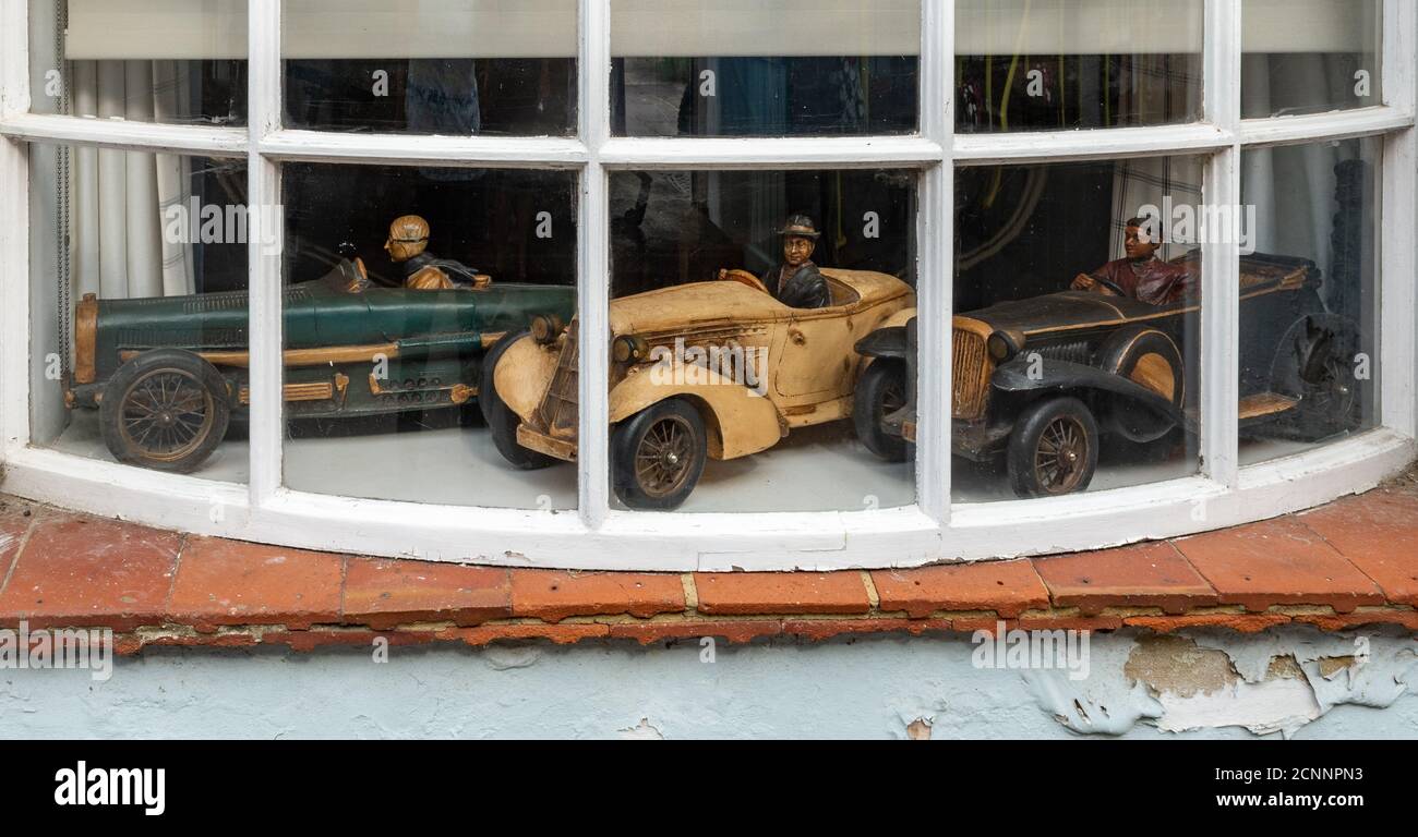 Three model classic cars and drivers on display in a window in the ...