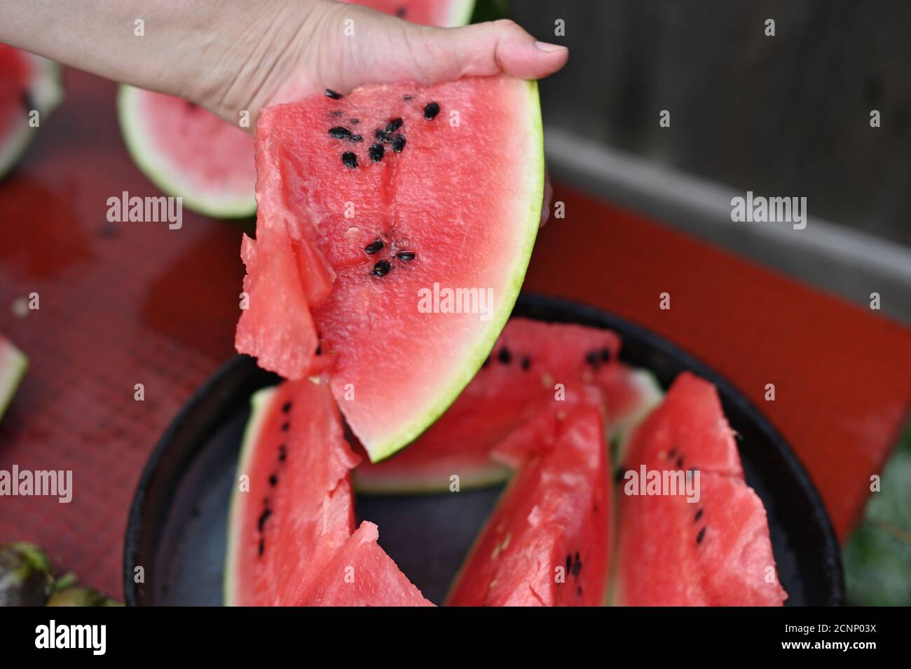 Hand reaching for a piece of sliced watermelon Stock Photo - Alamy