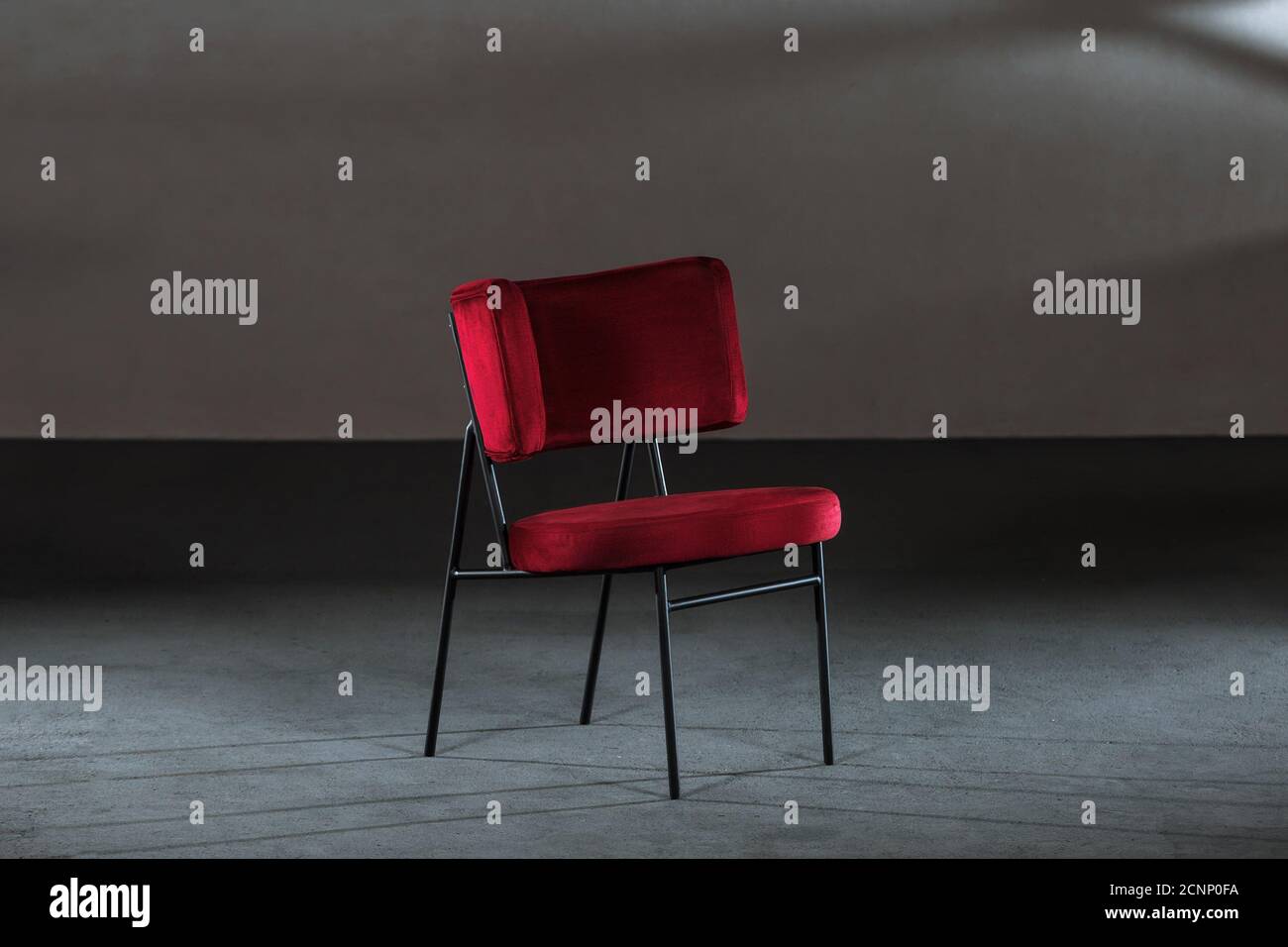 Comfy red wing chair in a studio with gray walls Stock Photo - Alamy