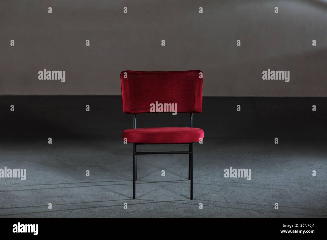 Comfy red wing chair in a studio with gray walls Stock Photo - Alamy