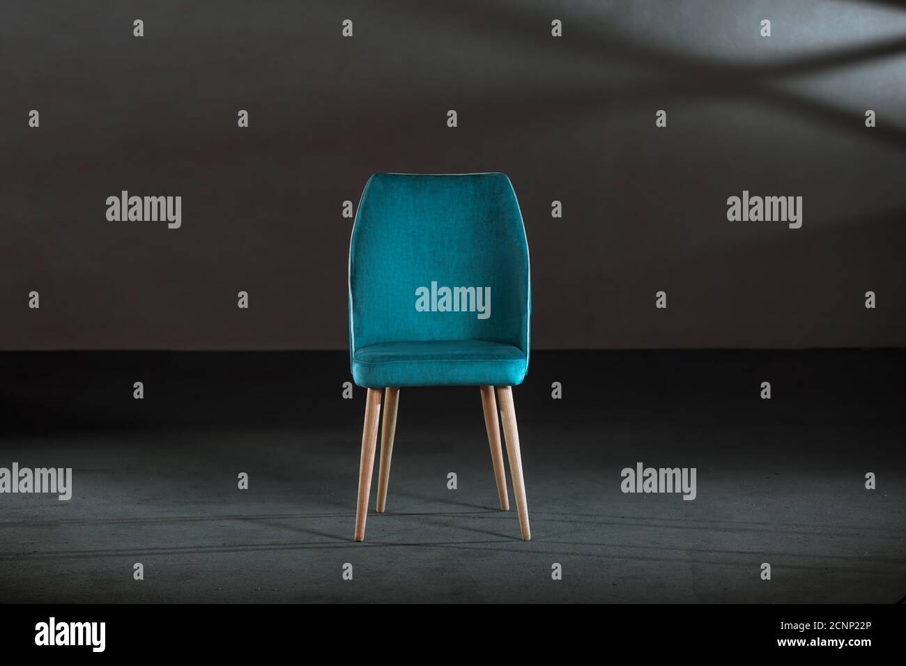 Comfy blue wing chair in a studio with gray walls Stock Photo - Alamy