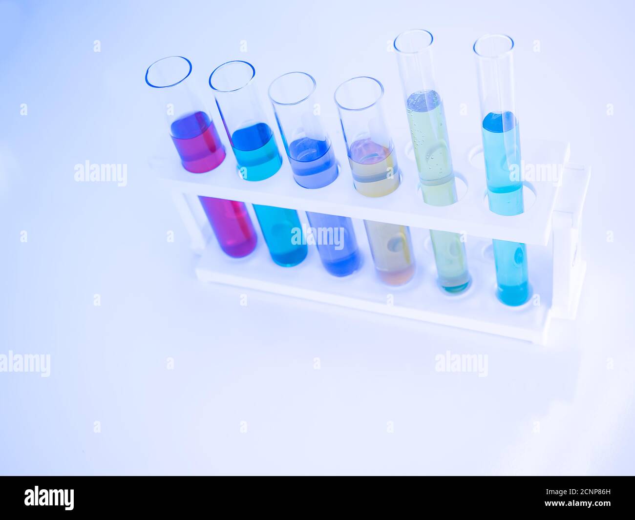 The test tube has a multicolored liquid inside. Put on a table for ...
