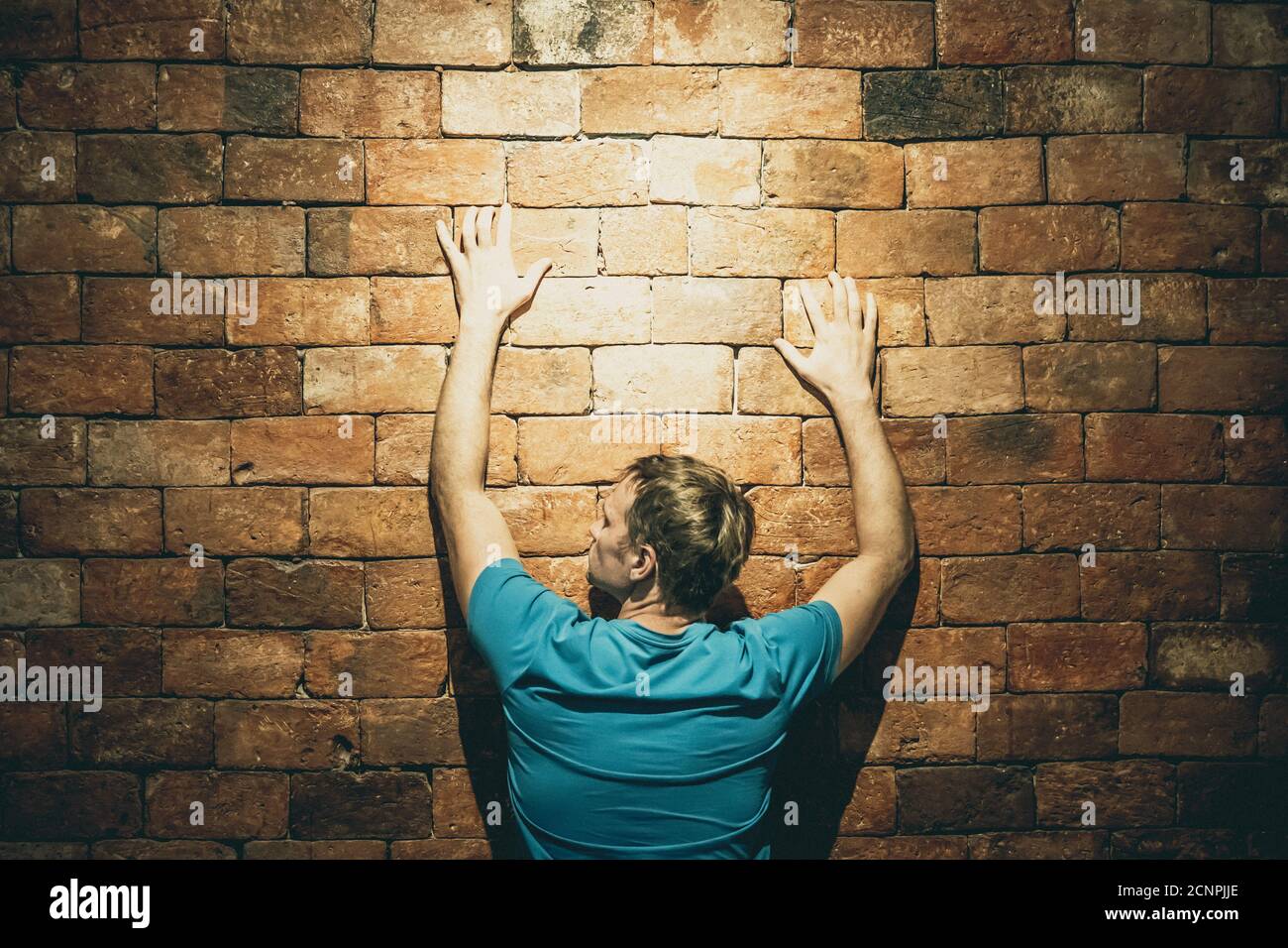 Rear view man under life crisis problems stand facing brown brick wall ...