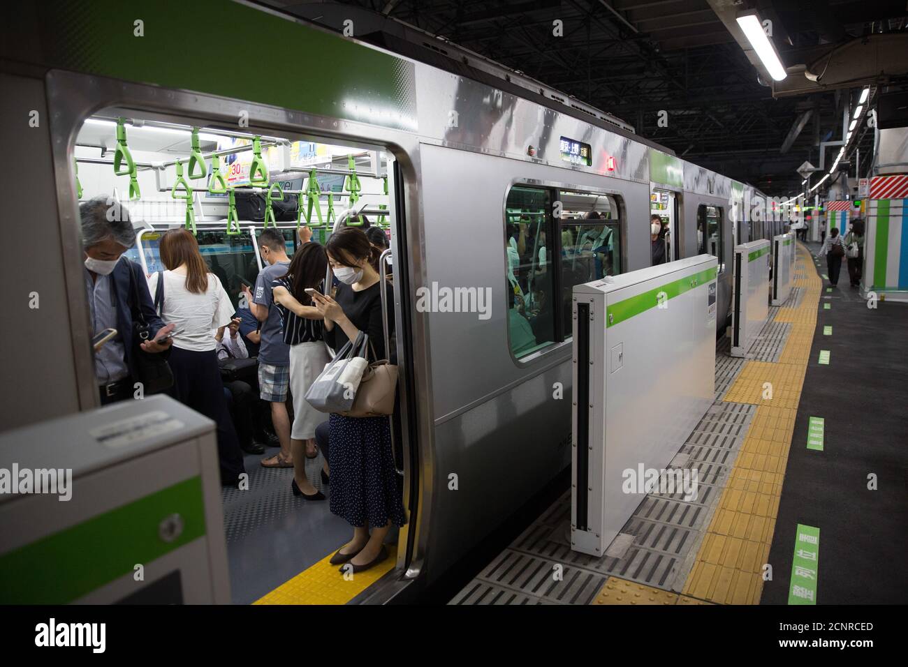 Commuters wearing face masks inside a train at the Hamamatsucho station ...